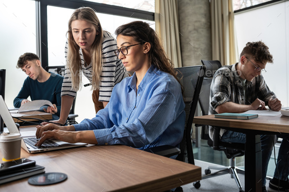 Programmers work alongside their colleagues in an office Stock Photo by milanzeremski